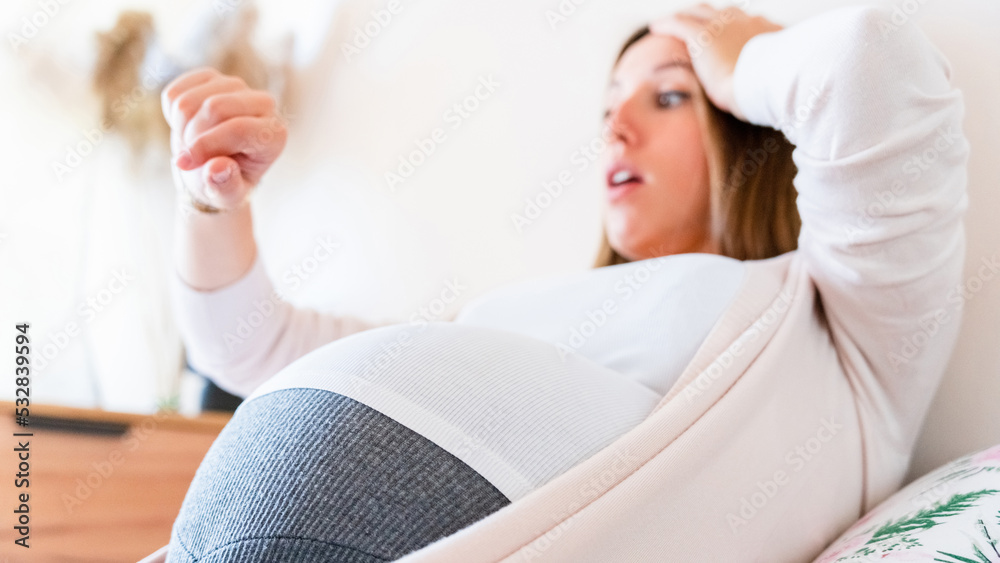 Pregnant pain contractions. Pregnant woman watching clock, holding baby ...