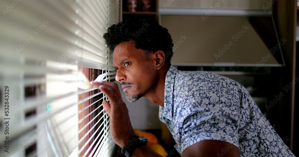 African man looking through window blinds Stock Photo | Adobe Stock
