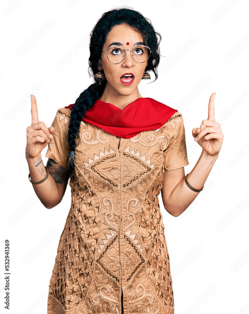 Young indian woman wearing traditional dress and glasses amazed and ...