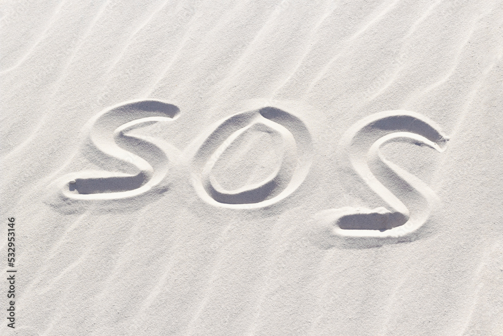 SOS written with finger on white sand, concept of missing and signal ...