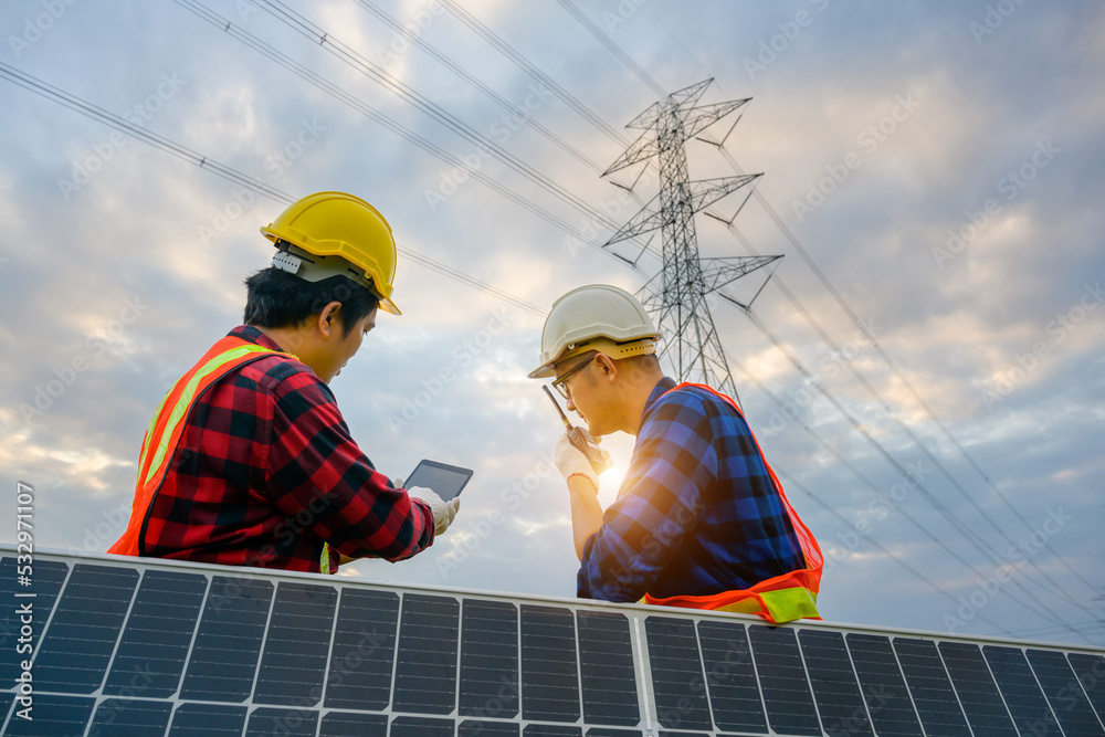 A team of two male electrical engineers using tablets to watch power ...