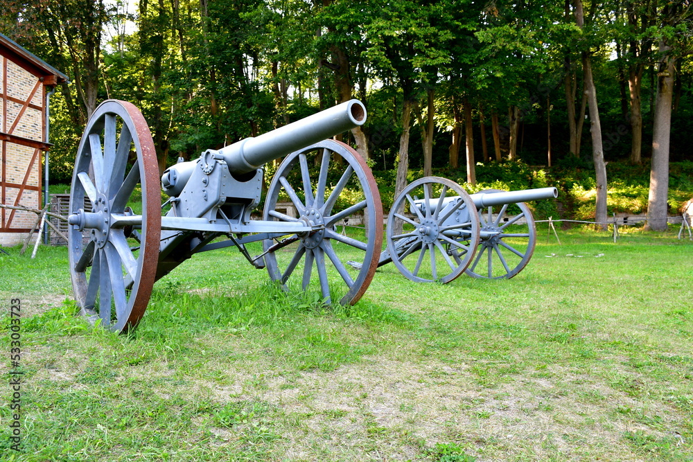 Two massive grey cannon replicas on two rusty wheels with base and ...