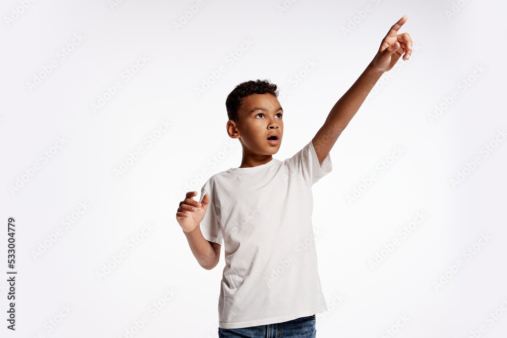 Shocked african little boy in white tee pointing and looking up ...