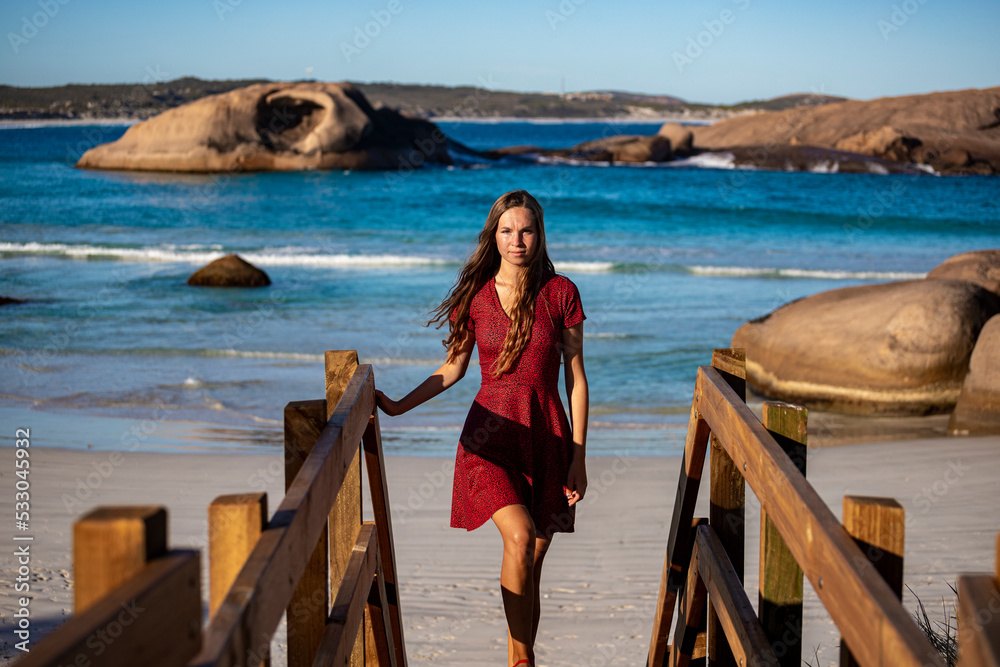 Back view of a long-haired girl in a red dress walking down the stairs ...
