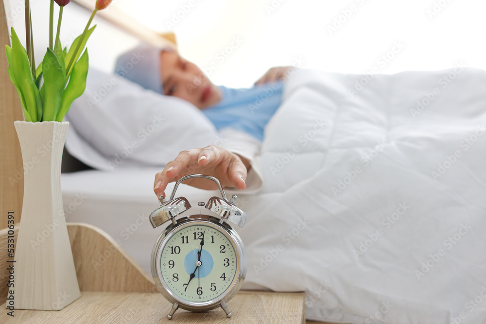 Oversleeping asian woman wearing white muslim sleepwear lying on bed ...