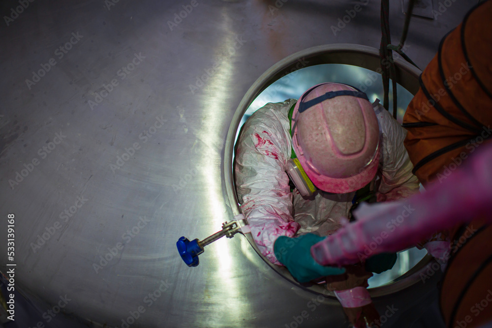 Top view male climbs up the stairs into the tank stainless chemical ...