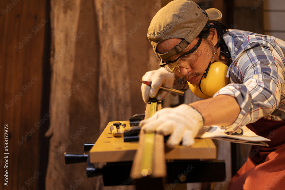Asian man Carpenter wearing PPE working use measuring tape on timber ...