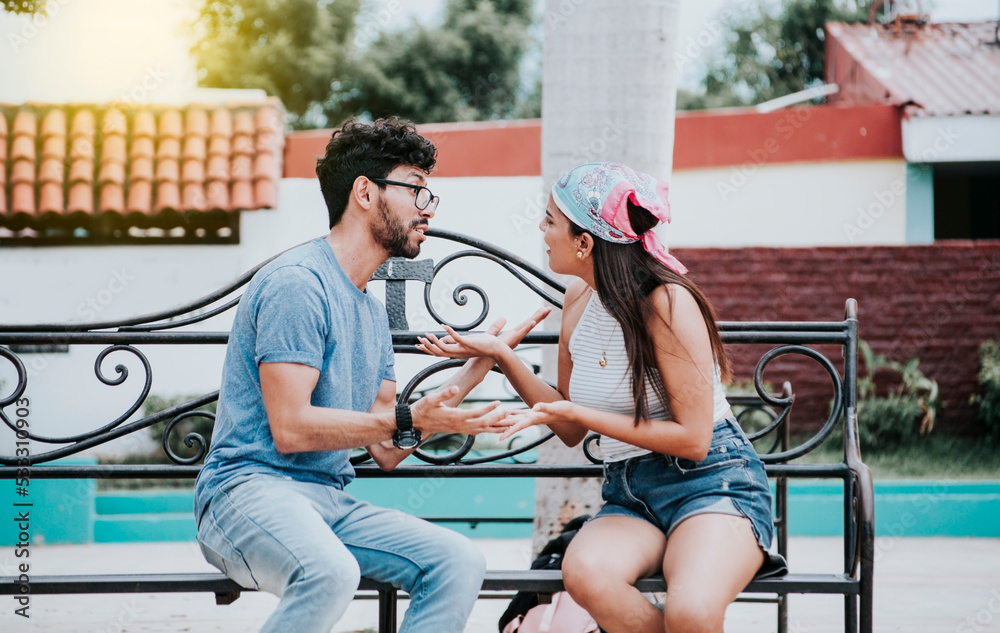 Man arguing with his girlfriend sitting in a park. Young couple arguing ...