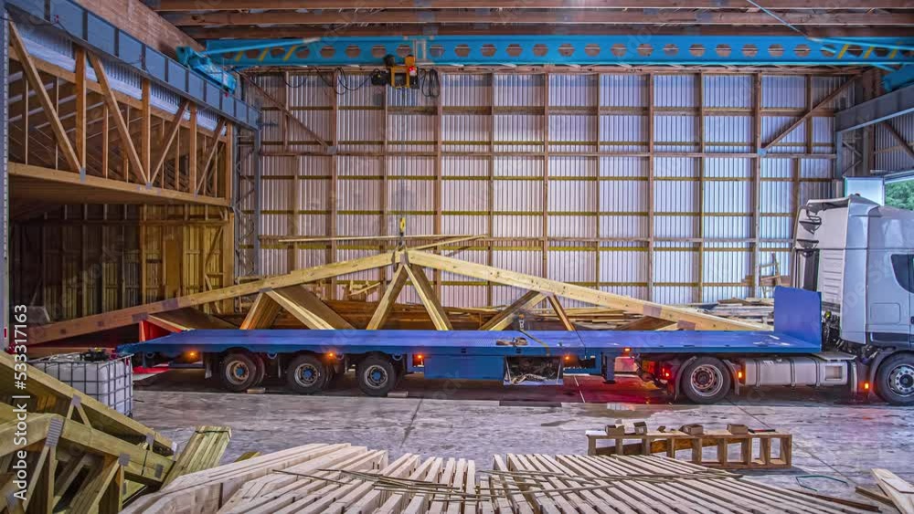 At a warehouse loading prefabricated roof trusses on a truck bed for ...