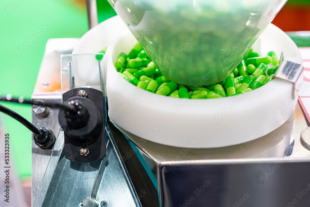 many empty green capsules in plastic hopper for manufacturing process ...