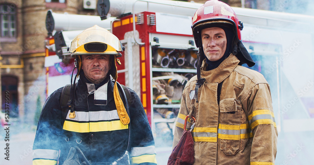 Medium plan of two firefighters in helmet and gull equipment standing ...