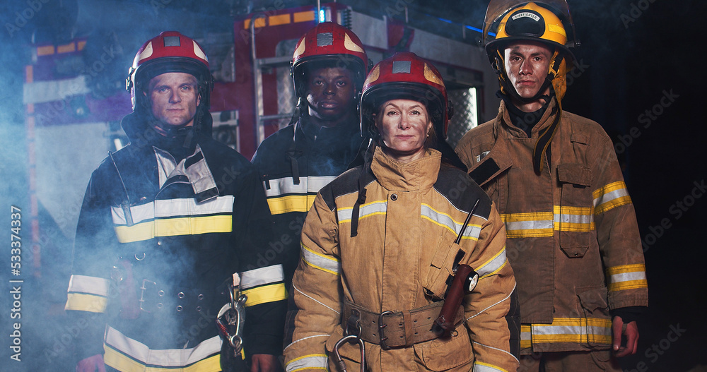 Middle plan of four firefighters approaching from fire van wearing full ...