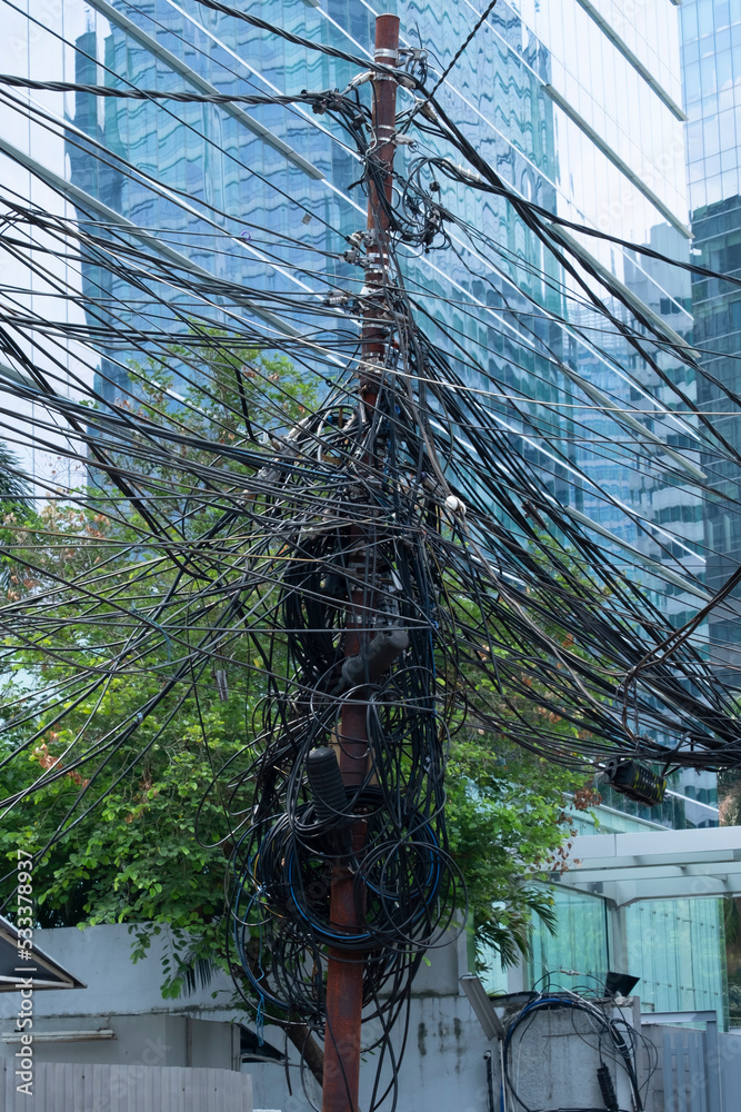 Vertical image of messy electricity wires on the pole. The chaos of ...