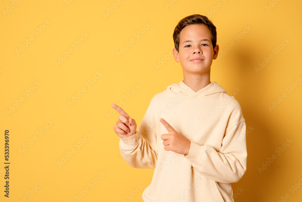 Portrait of cheerful boy pointing to the side - isolated over yellow ...