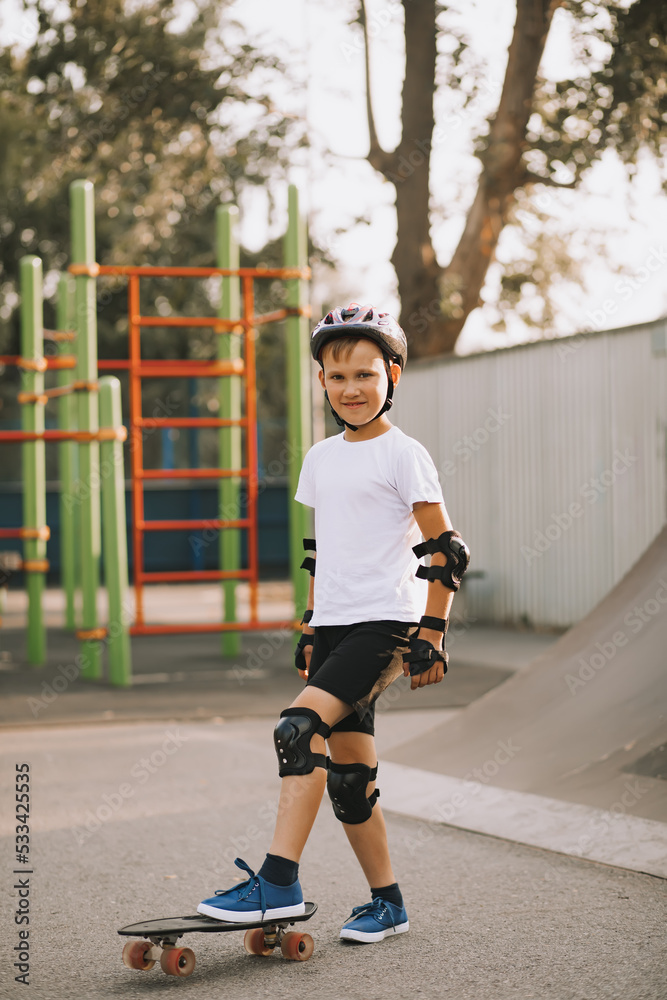 Cute kid boy in a helmet standing in a special area in skatepark and ...