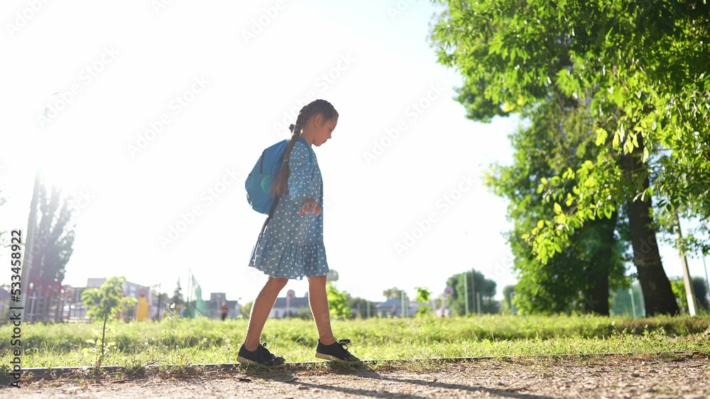 schoolgirl goes to school through the park along the path. concept of ...