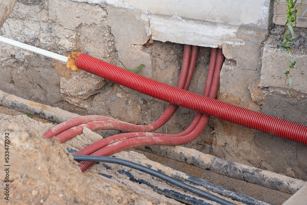 Electric cables in red corrugated pipe are buried underground on the ...
