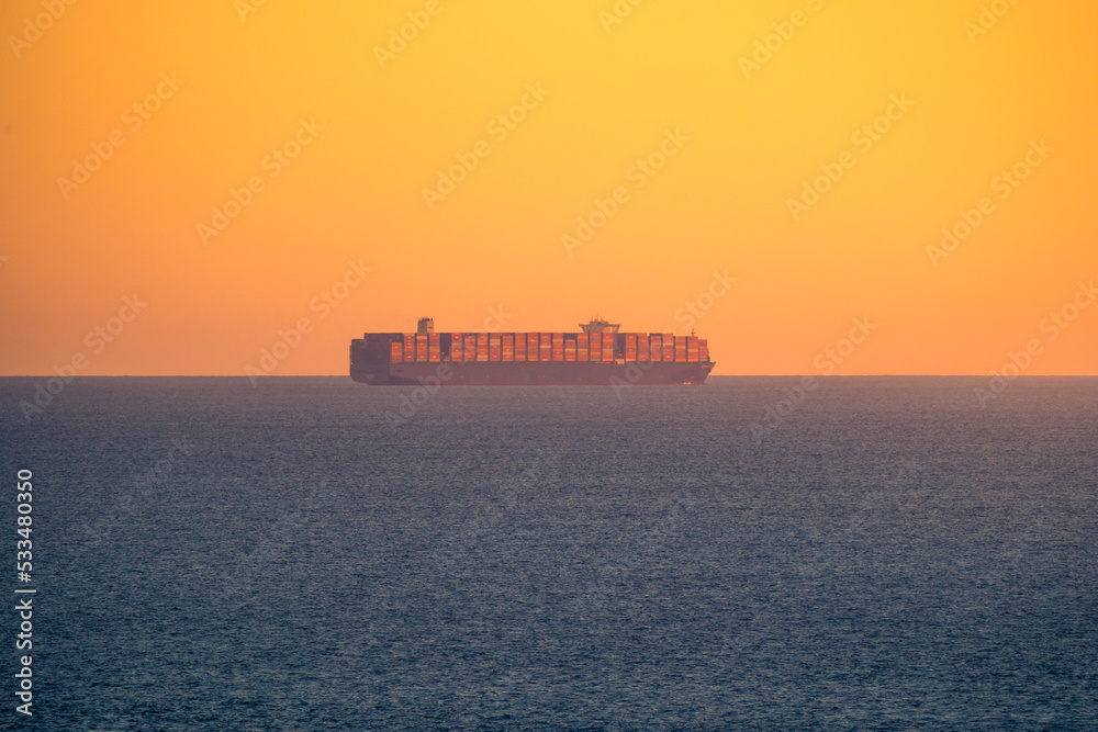 Sailing cargo ship in sea at sunset Stock Photo | Adobe Stock