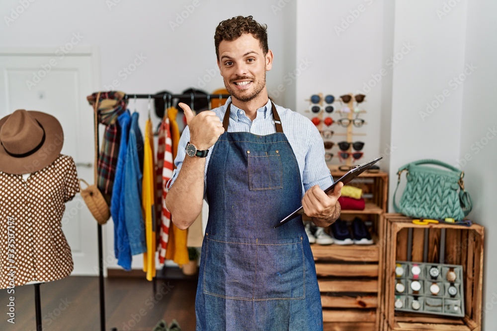 Handsome young man working as manager at retail boutique pointing to ...