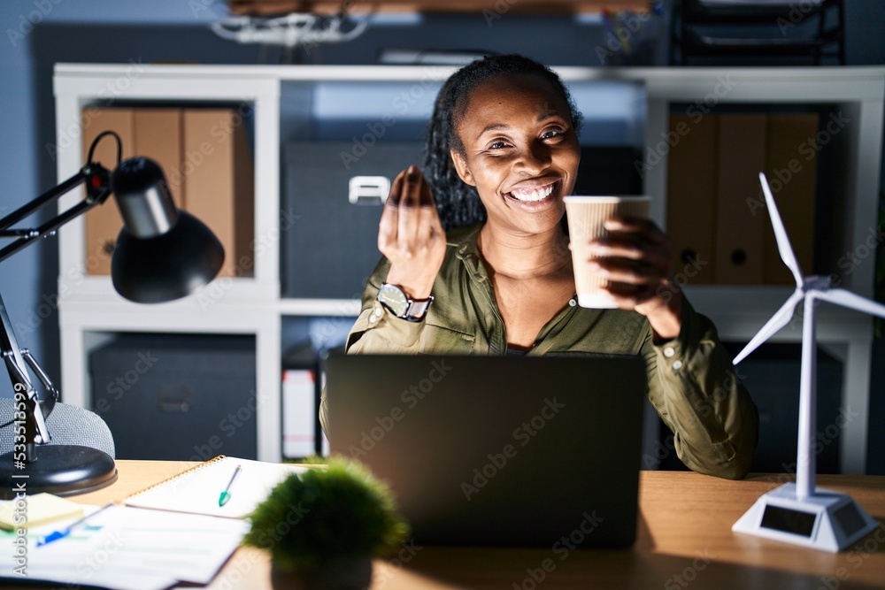 African woman working using computer laptop at night doing money ...