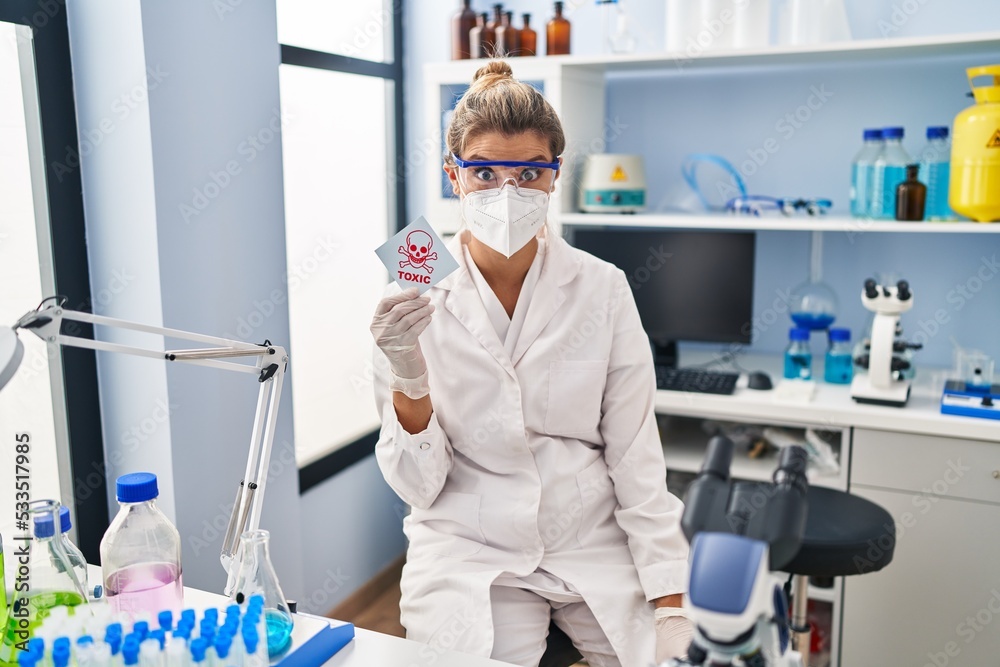 Foto de Young woman working at scientist laboratory holding toxic ...