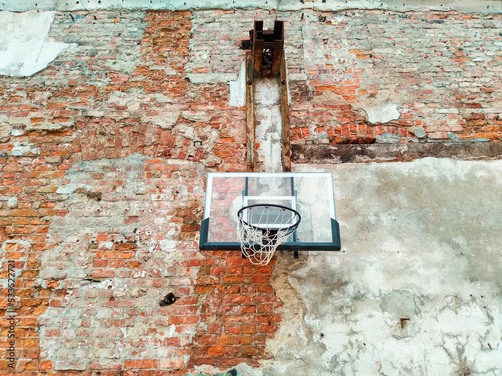 Old and worn outdoor basketball hoop net on the red brick wall ...
