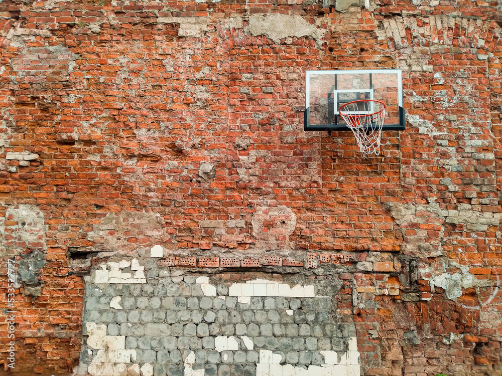 Old and worn outdoor basketball hoop net on the red brick wall ...