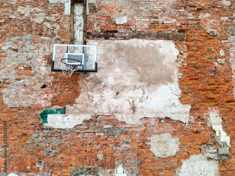 Old and worn outdoor basketball hoop net on the red brick wall ...