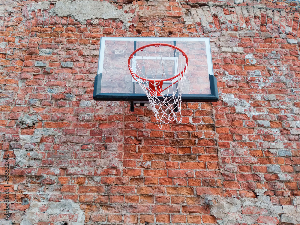 Old and worn outdoor basketball hoop net on the red brick wall ...