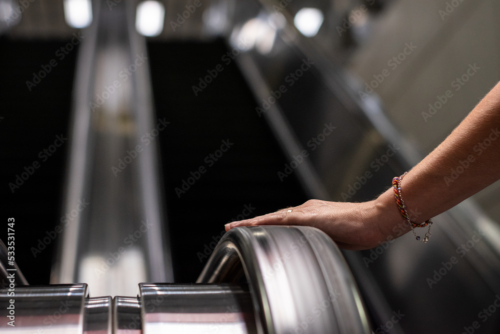 Persona apoyando la mano en baranda de escalera mecánica yendo hacia ...