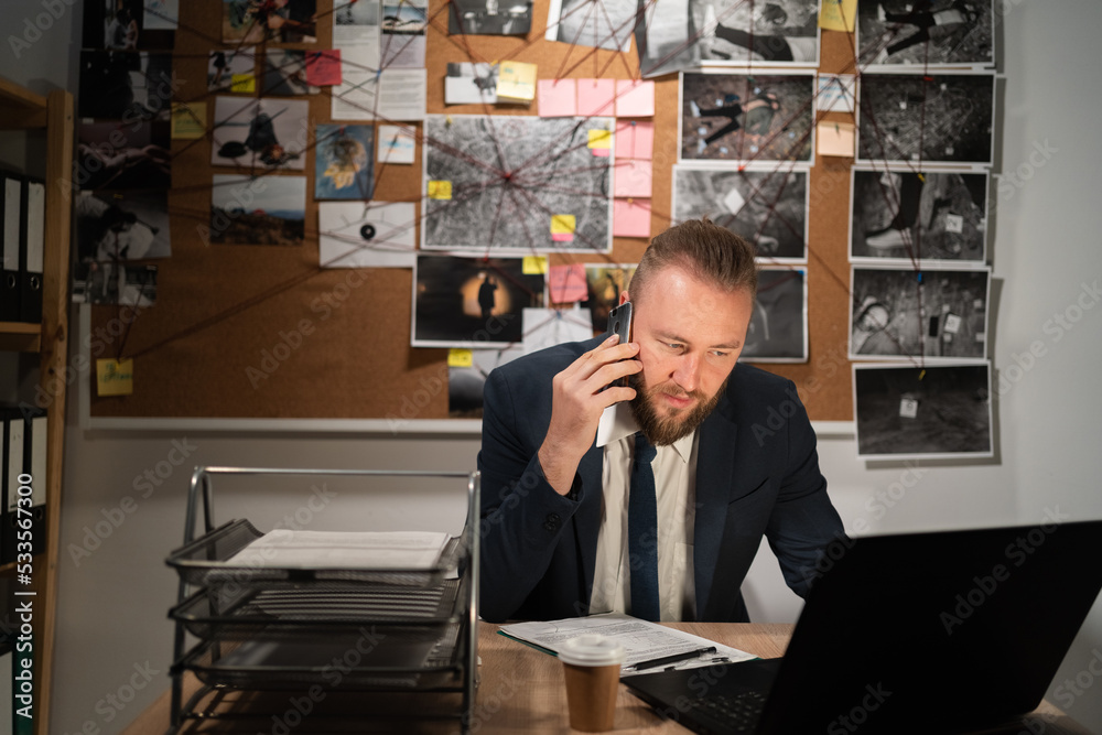 young detective sitting at police department talking to colleague on ...
