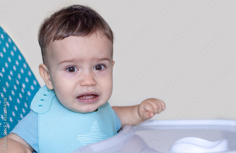 upset angry toddler sit in high feeding chair with silicone bib ...