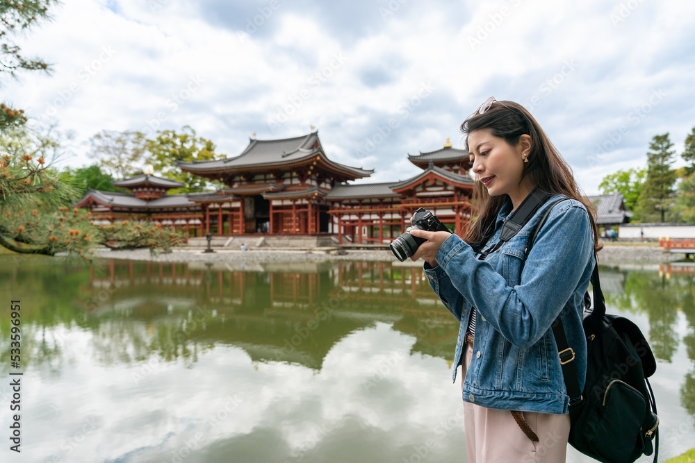 asian taiwanese female photographer checking photos in slr camera near ...
