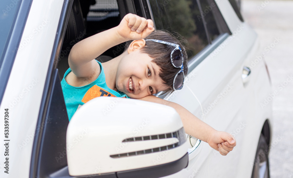 happy kid in white car looking in rear view retractable lateral mirror ...