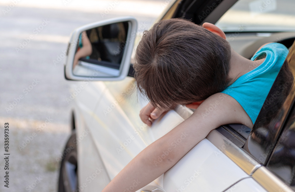 happy kid in white car looking in rear view retractable lateral mirror ...