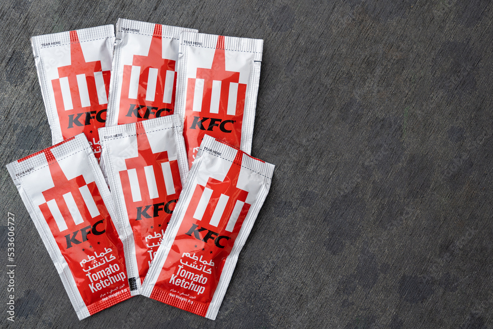 Packets of single serving KFC Tomato Ketchup on wooden background ...