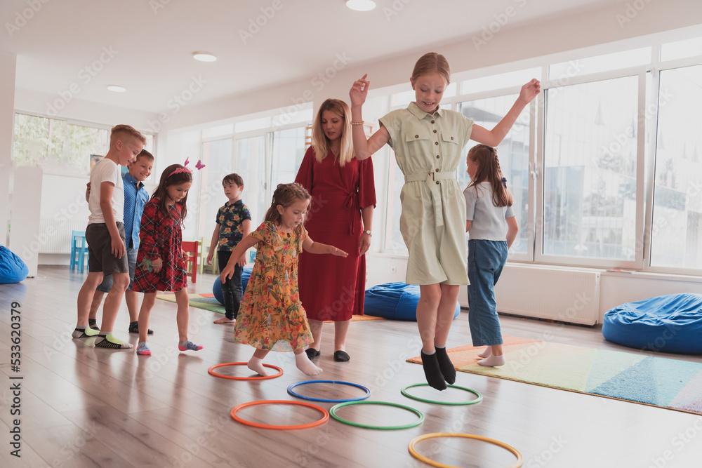 Small nursery school children with female teacher on floor indoors in ...