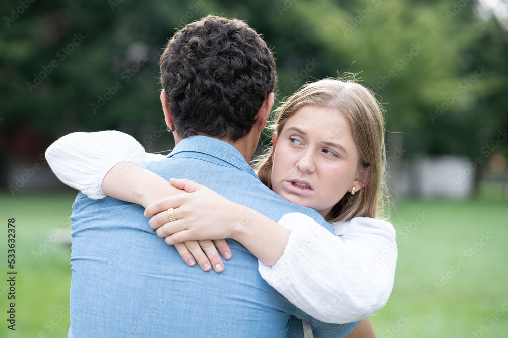 Dishonest teenager girl embracing boyfriend with nasty face. Infidelity ...