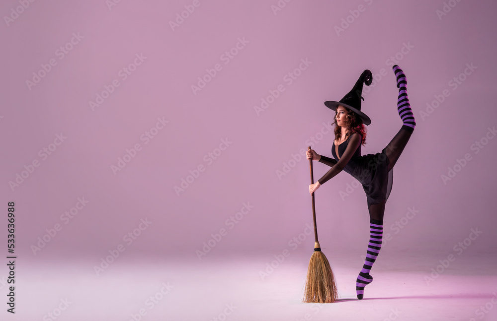 ballerina on pointe shoes in a black witch costume in a hat and with a ...