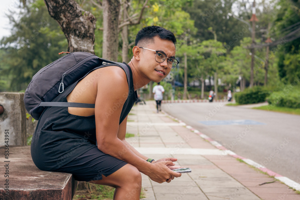 Filipino young man with eyeglasses and backpack holding cellphone ...