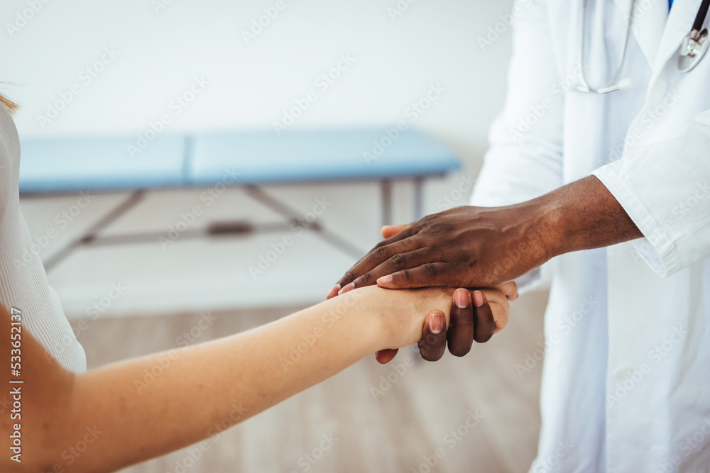 Friendly male doctor's hands holding female patient's hand for ...