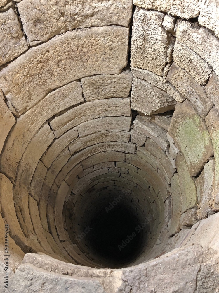 Deep stone pit. Residential water well in ancient building. Deep hole ...
