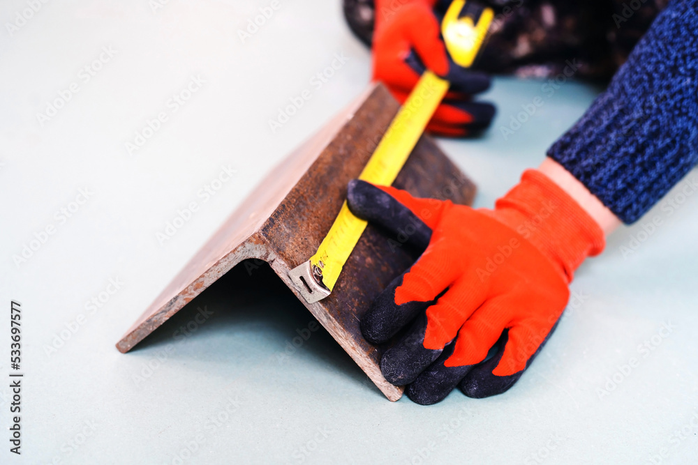 The process of measuring a metal corner with a ruler. A worker in ...