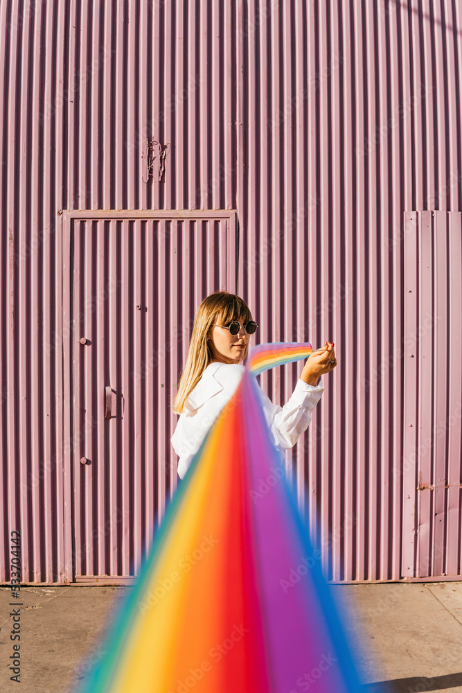 Young woman looking over shoulder holding rainbow colored ribbon in ...