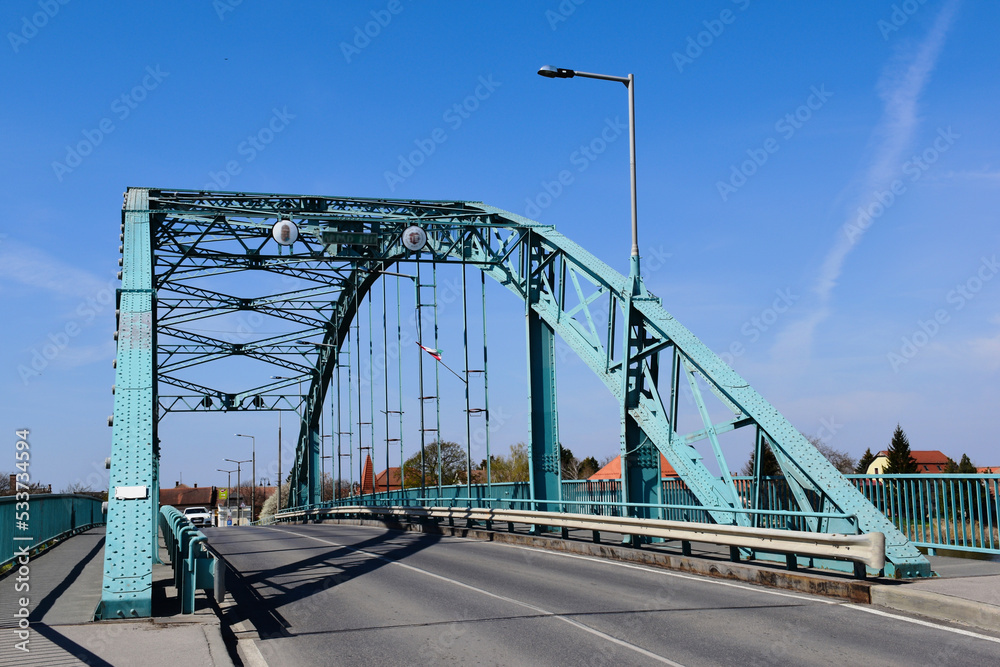 arched steel suspension bridge in diminishing perspective. blue sky ...