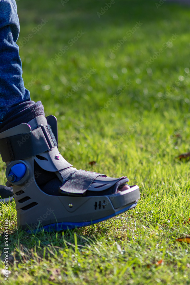 Boy with broken foot and orthopedic shoe or walker after bone fracture ...