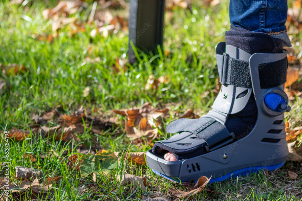 Boy with broken foot and orthopedic shoe or walker after bone fracture ...