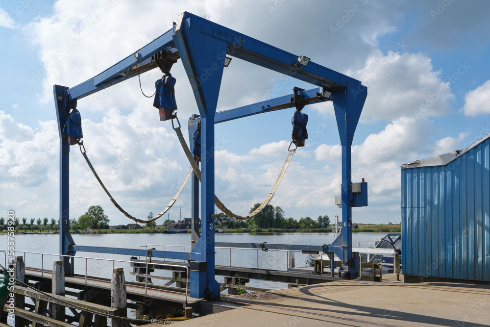 Empty boat travel lift in harbor under a blue sky with large clouds ...