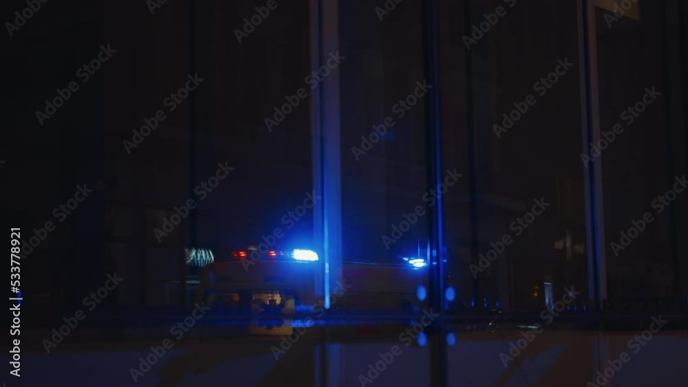 Window reflection of an ambulance vehicle with flashing siren lights at ...