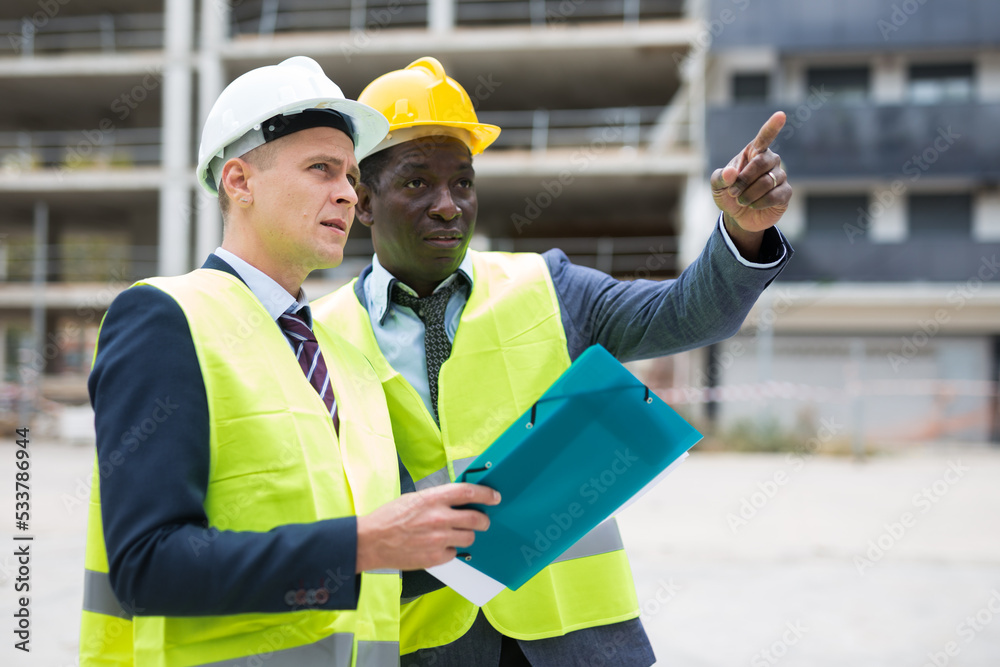 African-american and European men standing on construction site and ...